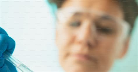 다른 액체를 떨어뜨리면서 액체 물질이 담긴 페트리 접시 위에 플라스틱 피펫을 들고 있는 여성 실험실 작업자의 장갑을 낀 손 사진