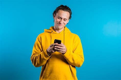 남자는 스마트 폰에서 응용 프로그램을 사용하여 문자 메시지 잘 생긴 젊은 남자 서핑 인터넷 와 휴대 전화 블루 스튜디오 배경