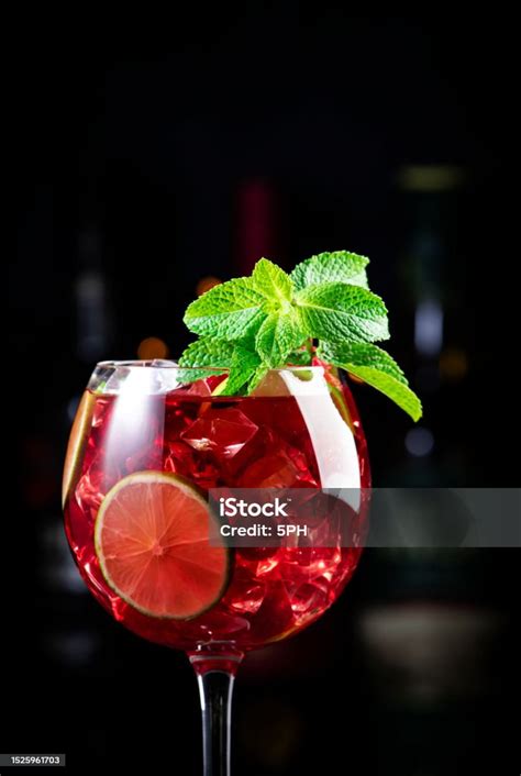 와인 잔에 데킬라 드라이 진 화이트 럼 보드카 주류 라임 라즈베리 및 얼음을 곁들인 로얄 레모네이드 알코올 칵테일 음료 검은색 바 카운터 배경 바 도구 및 병 Gin