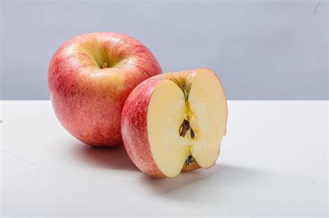 깨끗한 흰색 표면과 밝은 배경에 씨앗이 있는 전체 빨간 사과와 반 컷 사과는 육즙이 많은 질감 신선한 과육 및 잘 익은 건강한