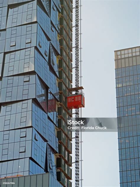 화물 건설 엘리베이터가 고층 빌딩 꼭대기로 올라갑니다 공사 중인 건물의 임시 엘리베이터 고층 빌딩 건설 발기 중인 건물에 있는 빨간 임시 엘리베이터 0명에 대한 스톡 사진