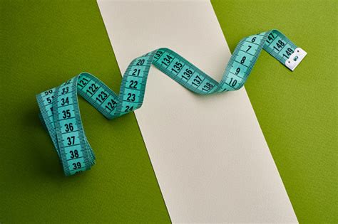 밝은 배경에 녹색 측정 테이프입니다 길이와 부피를 측정하기 위한 도구입니다 의류 산업 또는 인체의 부피를 측정하기 위한 테이프