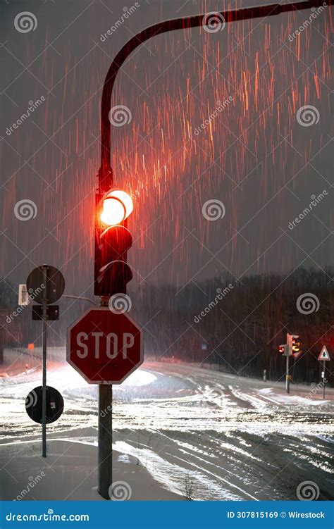 A Stop Sign Sitting In Front Of A Traffic Light On A Snowy Street Stock