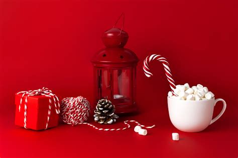 마시멜로 캔디 지팡이 선물 상자 포장 레이스 손전등 빨간색 배경 플랫 레이 복사 공간이있는 흰색 머그잔 겨울 전통 음료 음식