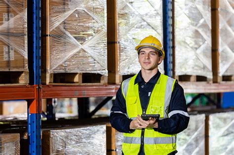 안전 유니폼과 안전모를 착용한 남성 전문직 근로자가 디지털 태블릿을 사용하여 창고의 선반에 있는 상품을 검사합니다 공장에서 제품을 검사하는 남자 노동자 수표 재고 20 24