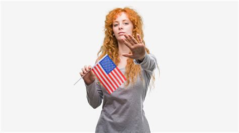 젊은 빨강 머리 여 자가 심각 하 고 자신감 표현 방어 제스처 정지 표시를 하 고 오픈 손으로 아메리카 합중국의 국기를 들고