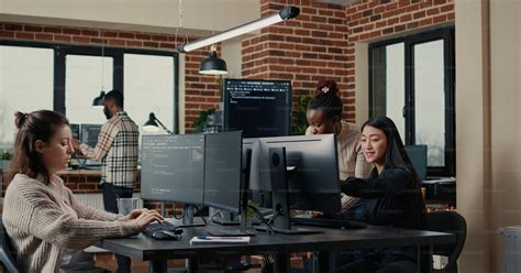 소프트웨어 엔지니어가 컴퓨터 키보드에 소스 코드를 입력하는 동안 동료들은 그룹 프로젝트를 위해 책상에 앉아 있습니다 온라인