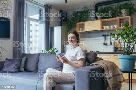 출산 휴가 임신 한 아름다운 여성은 집에서 소파에 앉아 휴대 전화와 신용 카드를 들고 집 옷을 입고 온라인으로 아기 제품을