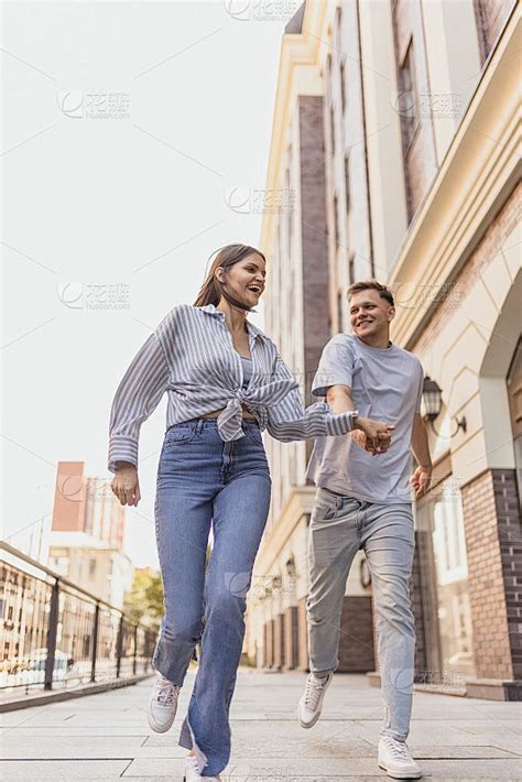 年轻幸福夫妇在运动的全身肖像。在温暖阳光的日子里漫步在城市里素材 花瓣网