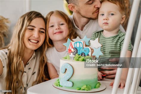 케이크 2 세의 생일 파티를 축하하는 행복한 가족 어머니 아버지는 아이들을 껴안고 있습니다 엄마 아빠 딸이 스튜디오에서 아들의 생일을 축하한다 생일 리셉션 축하 개념입니다