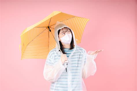 진지한 아시아 여성의 사진은 바이러스로부터 자신을 보호하고 질병을 잡기 위해 의료용 마스크를 쓰고 분홍색 배경에 우산 아래 서