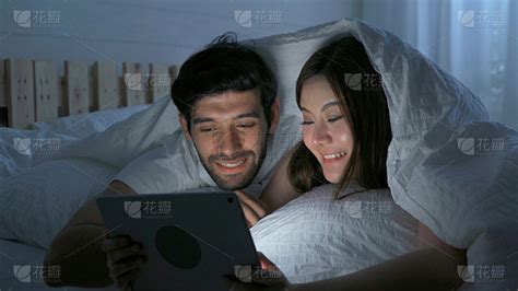 几个家庭。中东青年男子和亚洲女子快乐。人们在社交媒体上使用平板电脑，在家里卧室的床上睡觉。深夜的科技