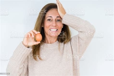 고립 된 배경 위에 신선한 계란을 들고 중 년 여성은 머리에 손으로 스트레스 수치심과 깜짝 얼굴이 충격 화가 좌절 두려움과