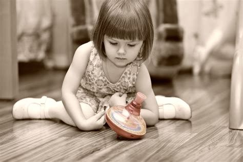 Фото Девочка сидит на полу и смотрит на юлу