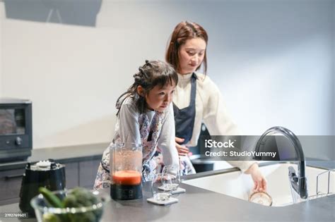 일본인 부모와 자식 30대 여성 20대 남성 6세 여자아이가 자택 주방에서 자른 당근과 꿀을 믹서기에 넣어 주스를 만들고 있습니다 2명에 대한 스톡 사진 및 기타 이미지
