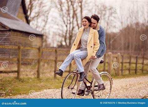Loving Transgender Couple With Woman Riding On Handlebars Of Bike In Autumn Or Winter