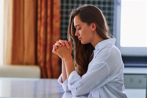 Premium Photo Lonely Calm Woman Believer Sits At Table With Praying