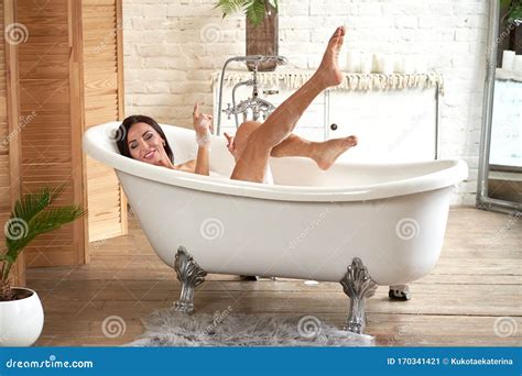 A Gorgeous Woman Is Enjoying Herself In A White Bathtub In A Bright