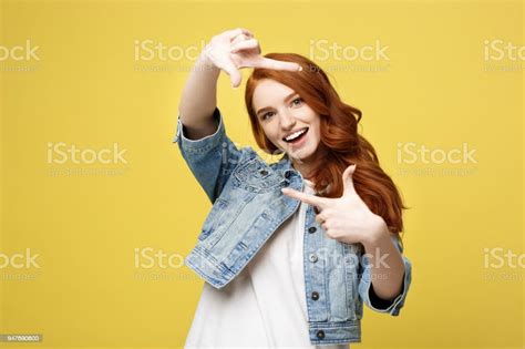 주 근 깨 Cheerfuly 손가락으로 카메라 프레임을 만드는 미소와 아름 다운 젊은 생강 여자의 초상화 노란 배경에 고립