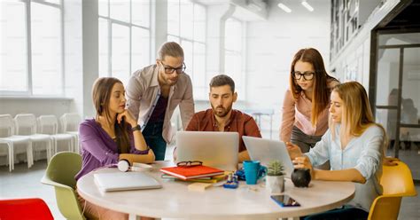 사무실의 원탁에 앉아 노트북과 함께 캐주얼하게 옷을 입은 젊은 동료 팀 사진 Unsplash의 원 이미지