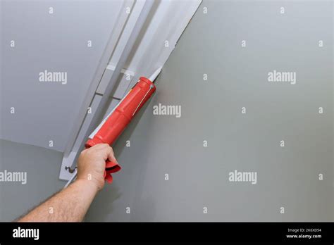 Construction Worker Fills Seam Between Cornice And Wall With Silicone Sealant Using Syringe