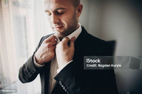 흰색 셔츠의 칼라를 들고 검은 정장에 세련된 신랑 방에 창 근처에 포즈 자신감있는 남자는 결혼식을 준비 아침에 준비 정장 사업가 검은색에 대한 스톡 사진 및 기타 이미지