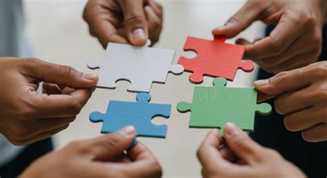 Four Hands Hold Interlocking Puzzle Pieces In White Red Blue And