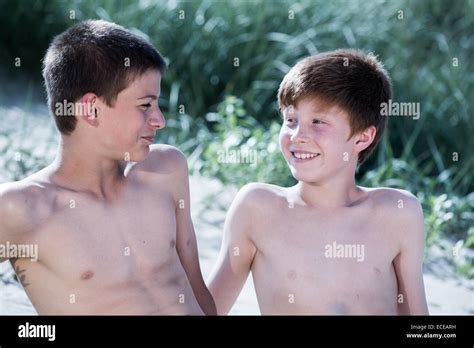 Two Boys Sitting On Beach Looking At Each Other Stock Photo Alamy