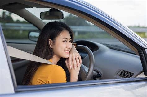 젊은 아름다운 아시아 여성은 새로운 차를 받고 그녀는 매우 행복하고 흥분했다 그녀는 앉아서 자동차의 모든 세부 사항을 만지고