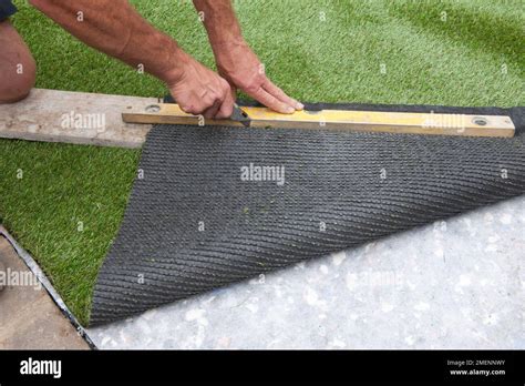 removing the grass free border from the edge of a sheet of artificial turf using a spirit level