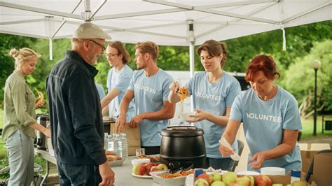 기부의 개념 노숙자들은 다민족 자원 봉사자 팀의 무료 자원 봉사 식사에 손을 뻗습니다 인도주의 원조 자선 단체는 도움이 필요한 사람들에게 식사를 제공합니다