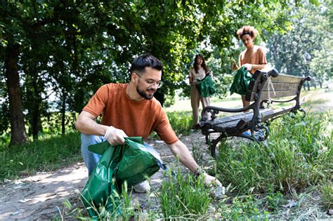 젊은 자원봉사자들이 함께 공원을 청소하고 쓰레기를 수거하고 쓰레기 봉투를 들고 있다 책임감 있는 부모와 친구들은 아이들이 자연