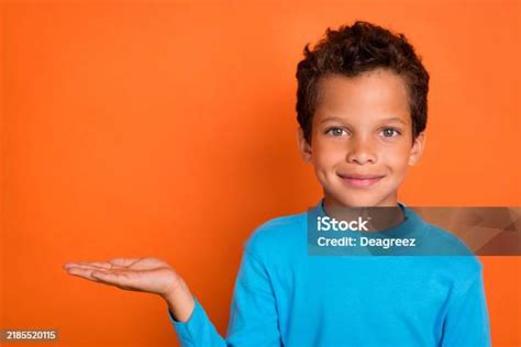 사랑 스럽다 작은 학생 소년 손바닥 홀드 Copyspace 쾌활한 모델의 사진 초상화 세련 된 블루 룩 오렌지 색상 배경에 고립 된 모습 8 9 살에 대한 스톡 사진 및