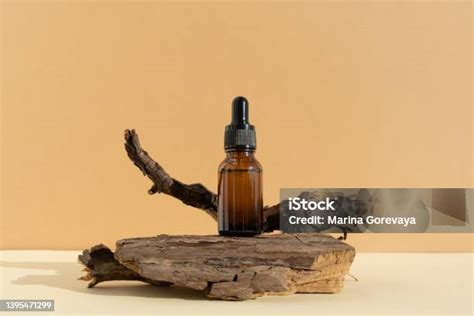 히알루 론산이 든 진한 호박색 유리 병 또는 베이지 색 배경의 마른 가지 근처의 얼굴 혈청 유기 성분을 가진 개념 천연 화장품 디자인의 공간을 복사합니다 정면보기