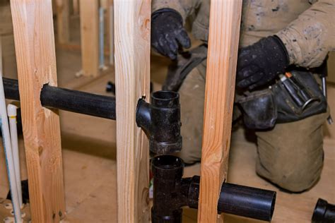 작업 영역에 Pvc 드레인 파이프를 설치하기 위한 피팅이 있는 접착제를 사용하는 작업자 60 64세에 대한 스톡 사진 및 기타