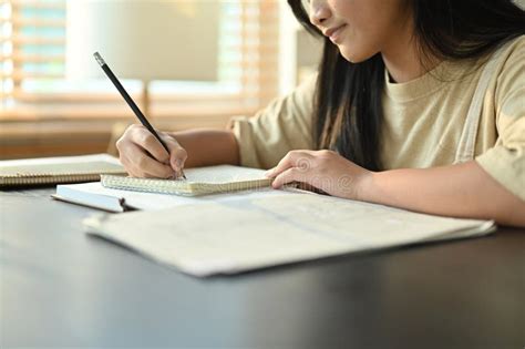 Focused Asian Girl Writing Task Doing Homework While Sitting At Table