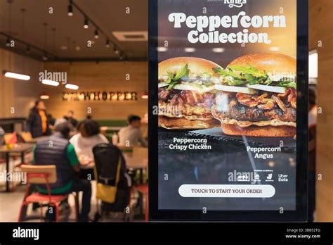 Eat In Customers Enjoy Meals At Burger King Diner Behind Large Led Menu