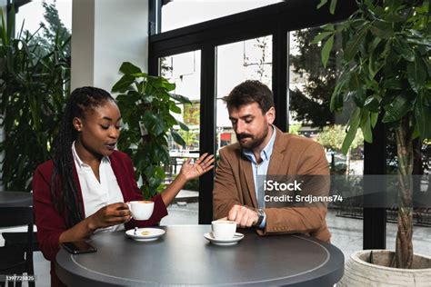 커피 숍에 앉아 커피를 마시고 일에 대해 토론하는 두 명의 젊은 비즈니스 프리랜서 아프리카 계 미국인 여성이 자신의 직업에서