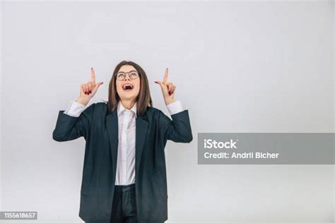 검은 양복을 입고 서서 미소를 지으며 위를 올려다 보며 텍스트 나 제품의 카피 스페이스에서 손가락을 가리키고있는 예쁜 젊은 사업가 가리키기에 대한 스톡 사진 및 기타 이미지