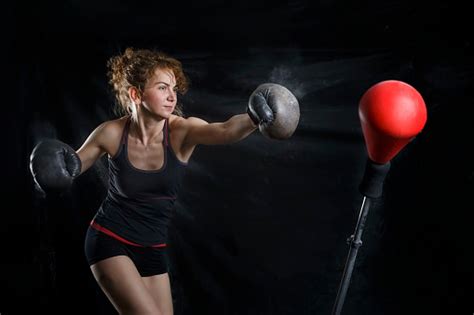 권투 장갑 권투 선수 여자 레드 샌드 백을 명 중 한다 킥복싱과 싸움 스포츠 개념입니다 어두운 배경입니다 텍스트 복사 공간에 대 한 공간입니다 가방에 대한 스톡 사진 및