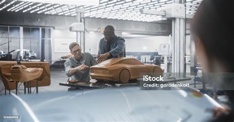 자동차 디자이너 모델러 및 엔지니어로 구성된 팀이 스튜디오에서 미래형 자동차를 만들기 위해 노력하고 있습니다 디지털 태블릿에 차량 스케치를 그리는 여성 두 명의 디자이너가