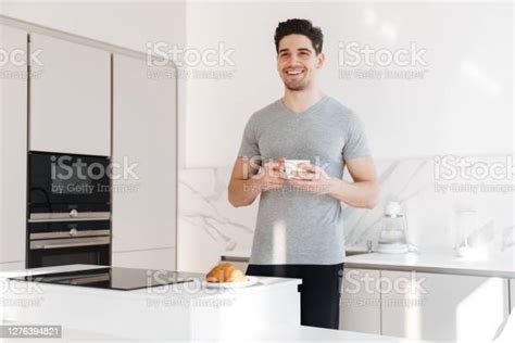 아파트에서 아침 식사를하면서 캐주얼 한 옷을 입고 미소 짓고 커피 한 잔을 들고있는 성인 남성의 초상화 T 셔츠에 대한 스톡 사진 및 기타 이미지 Istock