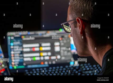 Cybersecurity Professional Analyzing Data On Multiple Screens In A Low Light Workspace For