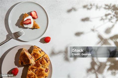 크림과 딸기를 곁들인 영국 스콘 화창한 날에 회색 테이블에 삼각형으로 자른 수제 딸기 스콘 전통적인 영어 만두 상단 보기 공간을