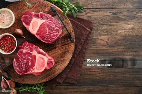 오소 부코 생 스테이크 고기 바베큐 고기 원시 신선한 크로스 컷 송아지 정강이와 조미료 후추 로즈마리 백리향 및 오래된 나무 배경에 소금 골수로 쇠고기 다리 슬라이스