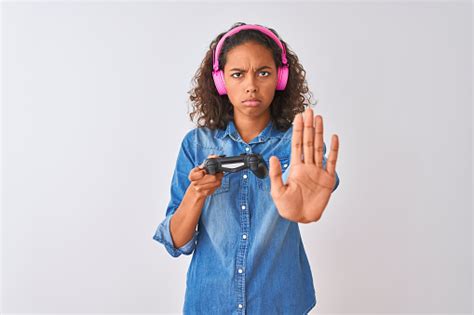 브라질 게이머 여자 는 심각하고 자신감 표정 방어 제스처와 정지 기호를하고 열린 손으로 고립 된 흰색 배경을 통해 헤드폰을