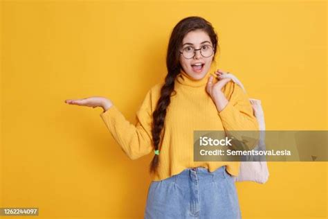 기절한 표정을 가진 젊은 여성의 이미지는 입을 열고 세련된 셔츠와 청바지를 짧게 입고 손바닥을 옆으로 벌리고 놀랍고 놀랍습니다 광고에 대한 스톡 사진 및 기타 이미지