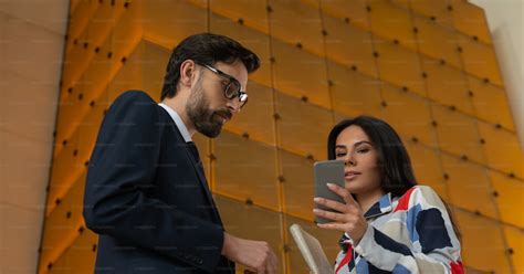 현대적인 사무실 홀에 서서 여자 손에 스마트폰 화면을 보고 있는 두 명의 비즈니스 동료 사진 Unsplash의 양복 이미지