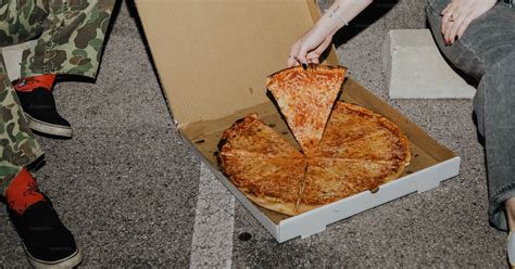 한 여자가 상자에서 피자 한 조각을 꺼내고 있다 사진 Unsplash의 재미 이미지