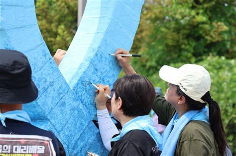 폭발로 폐허가 된 공장에서 참석자들이 하늘색 상징물에 오마이포토